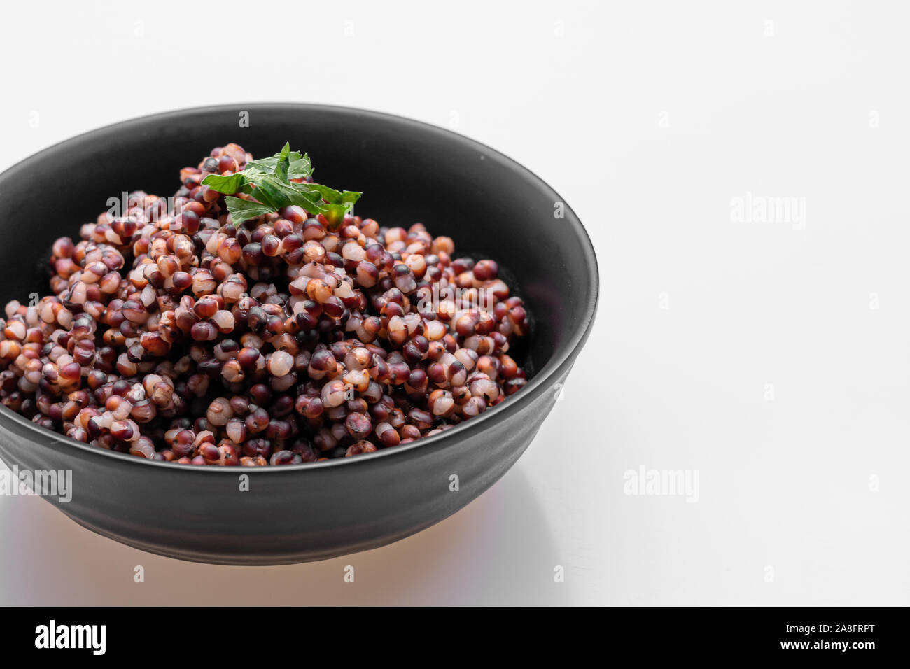 Cooked Sorghum (also known as sorgo) in a back bowl, isolated Stock ...