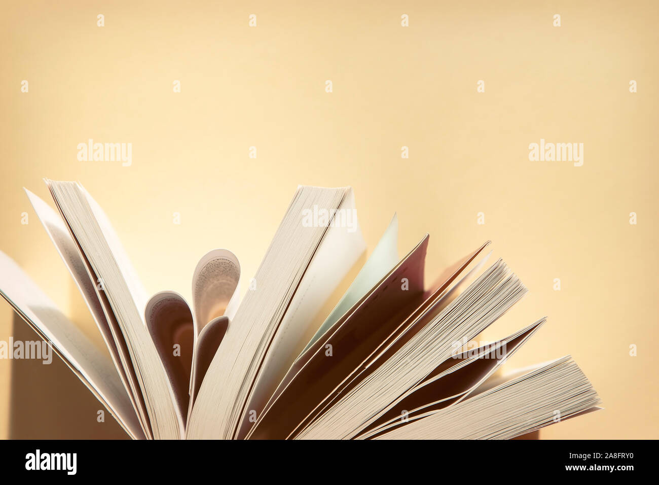 Open book over yellow background close up Stock Photo - Alamy