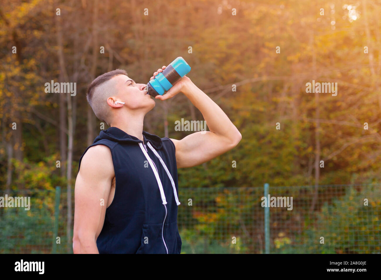 Young man drinking water from bottle while jogging in the morning ...