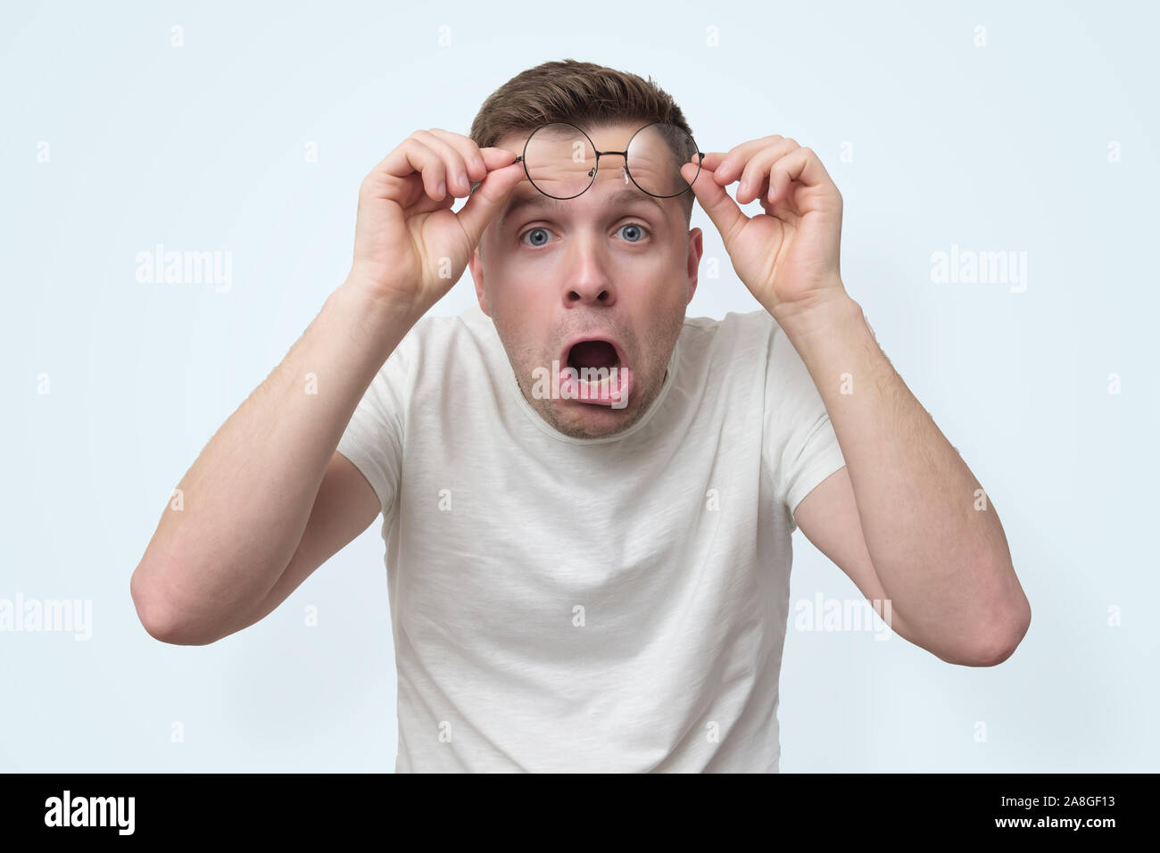 Surprised handsome man in glasses seeing something interesting. He is ...