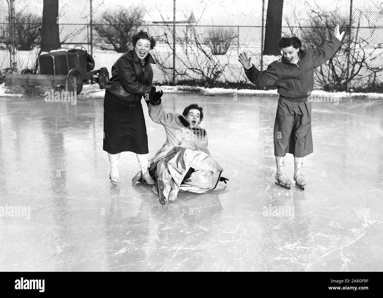 Three women have fun on the ice on a flooded baseball diamond along ...
