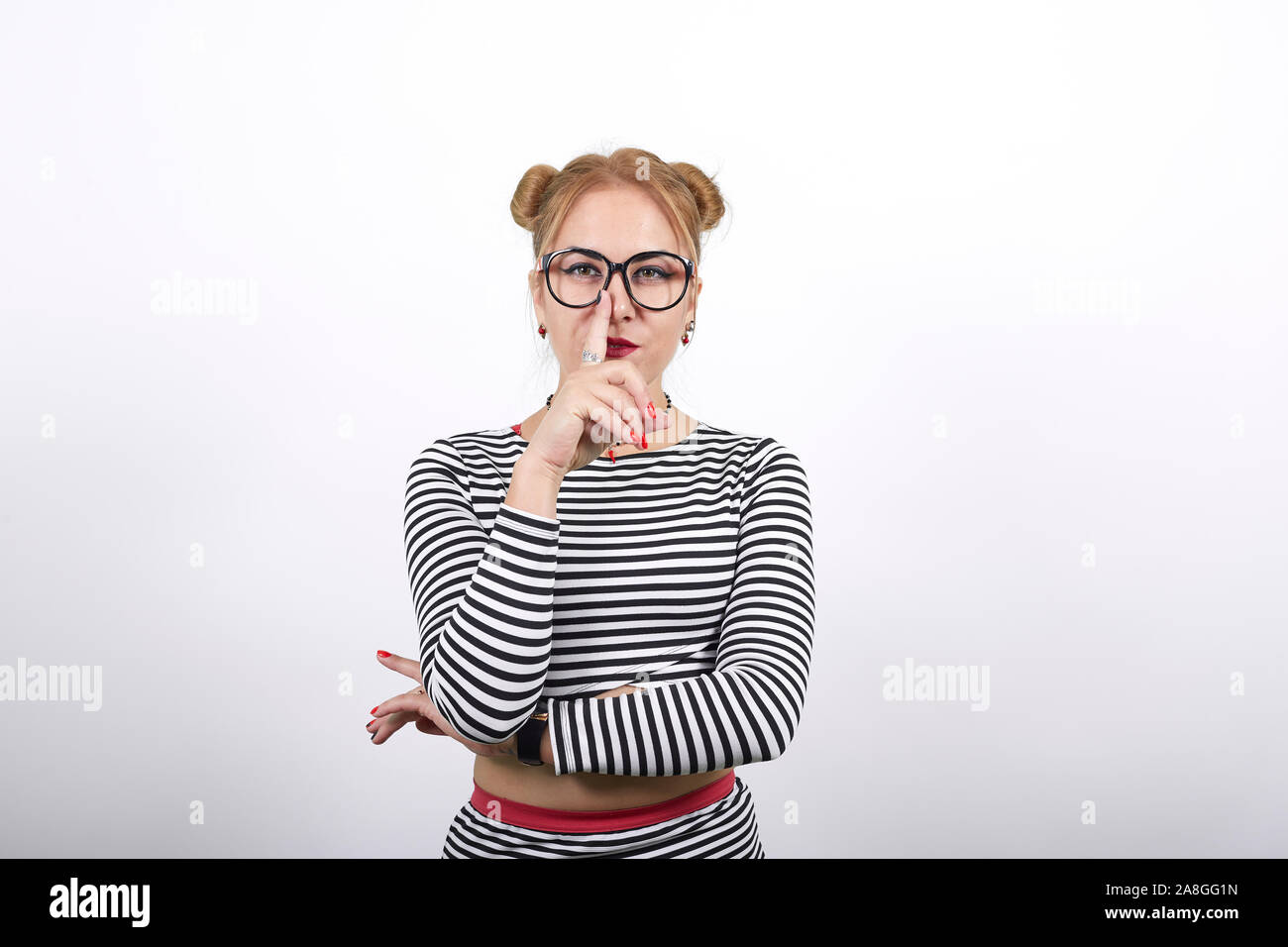 Portrait of cute smiling young woman in striped shirt putting hand up ...