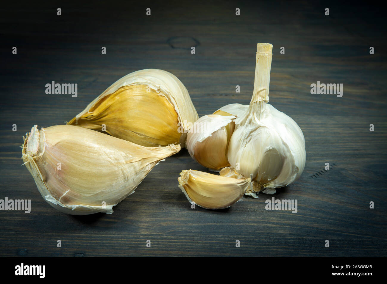 Elephant garlic (Allium ampeloprasum) regular garlic cloves on a rustic ...