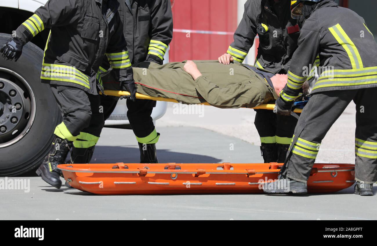 Medical team of four stretcher bearers carring an injured person after ...