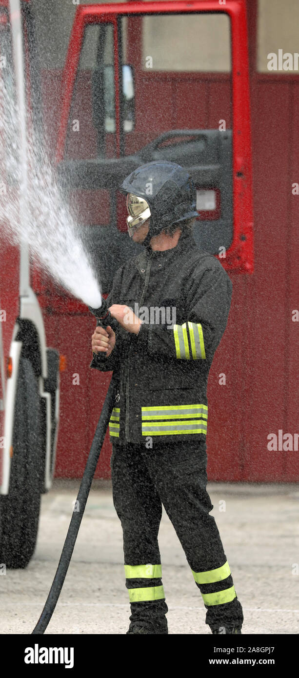 firefighter with uniform during the drill using the hydrant with foam ...
