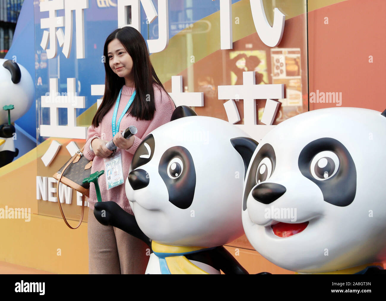 Shanghai, China. 8th Nov, 2019. A visitor poses for photos with Jinbao ...