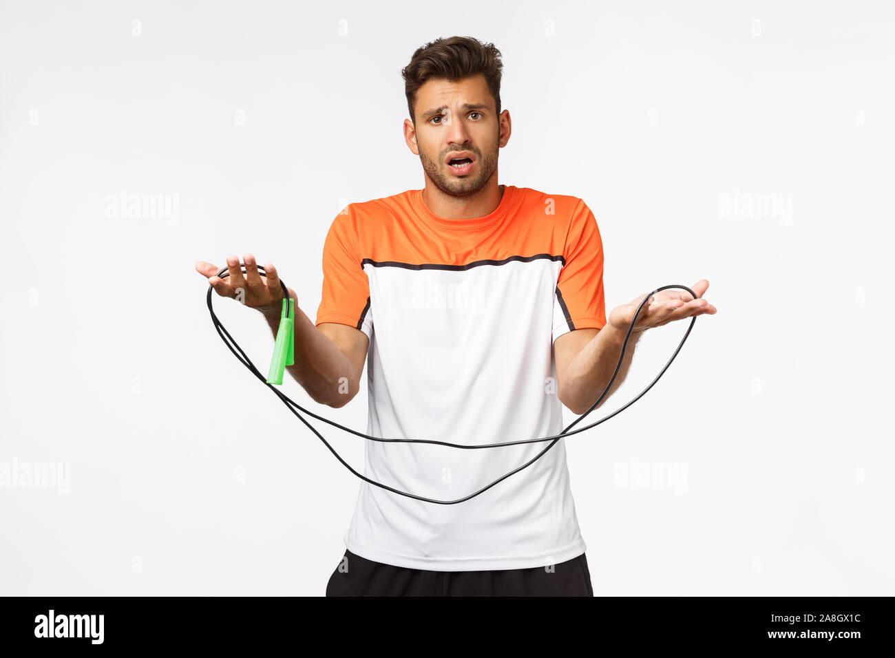Gloomy handsome young guy dont know how use skipping rope, cant jump ...