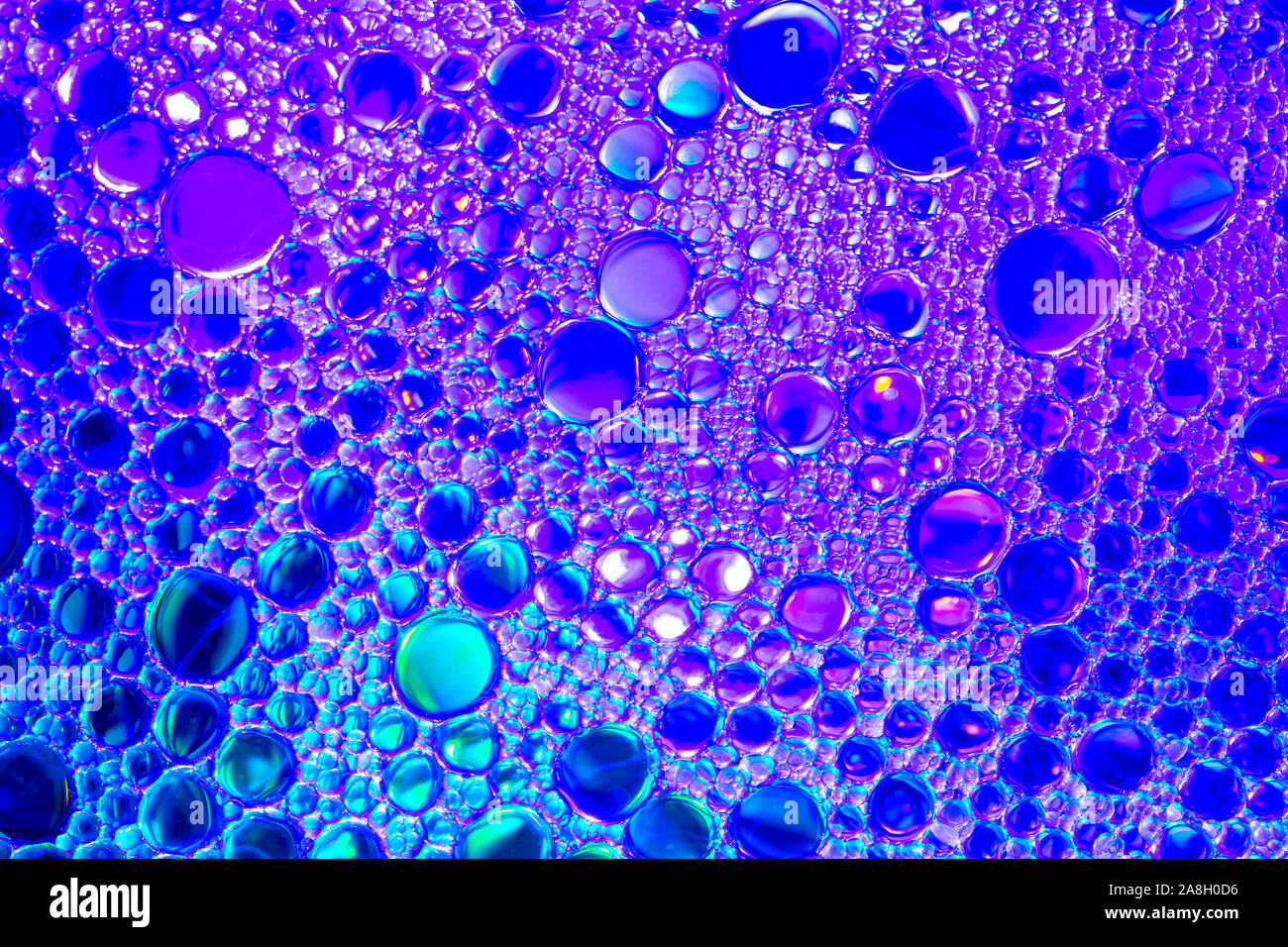 Colorful drops of oil on the water. Blue and violet colored circles and ...