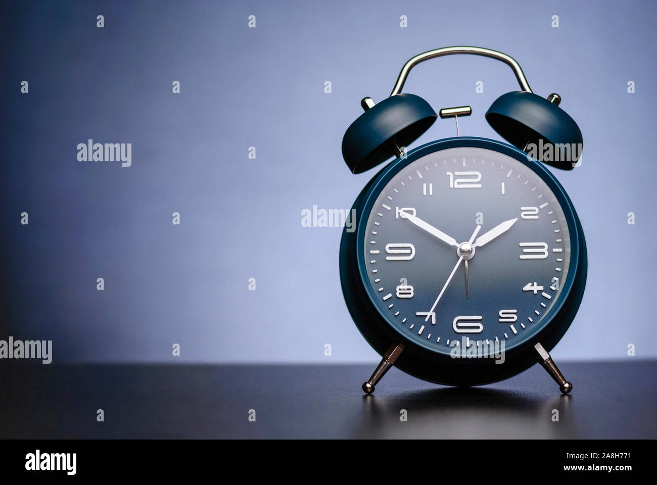 Traditional alarm clock with bells on blue background with copy space ...