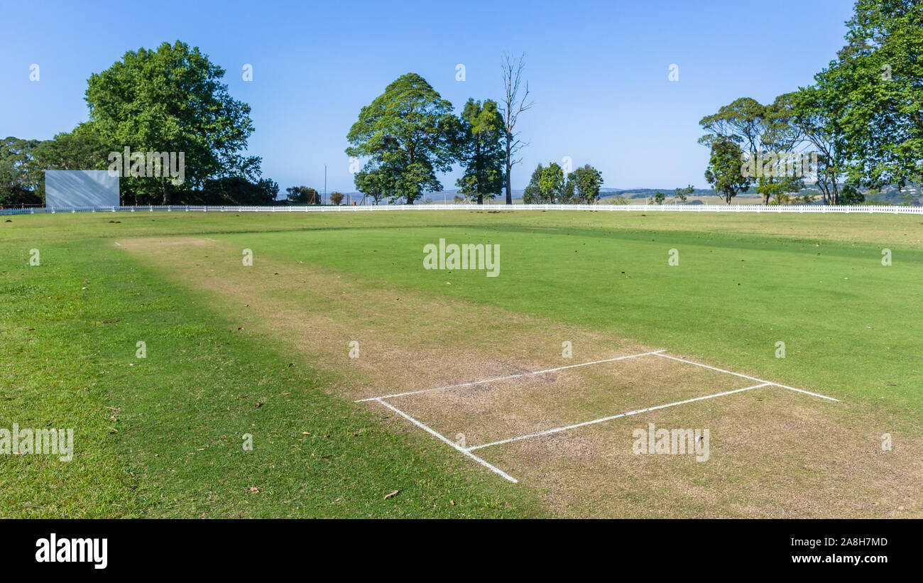 Scenic cricket grounds from white boundary fence of grass field astro ...