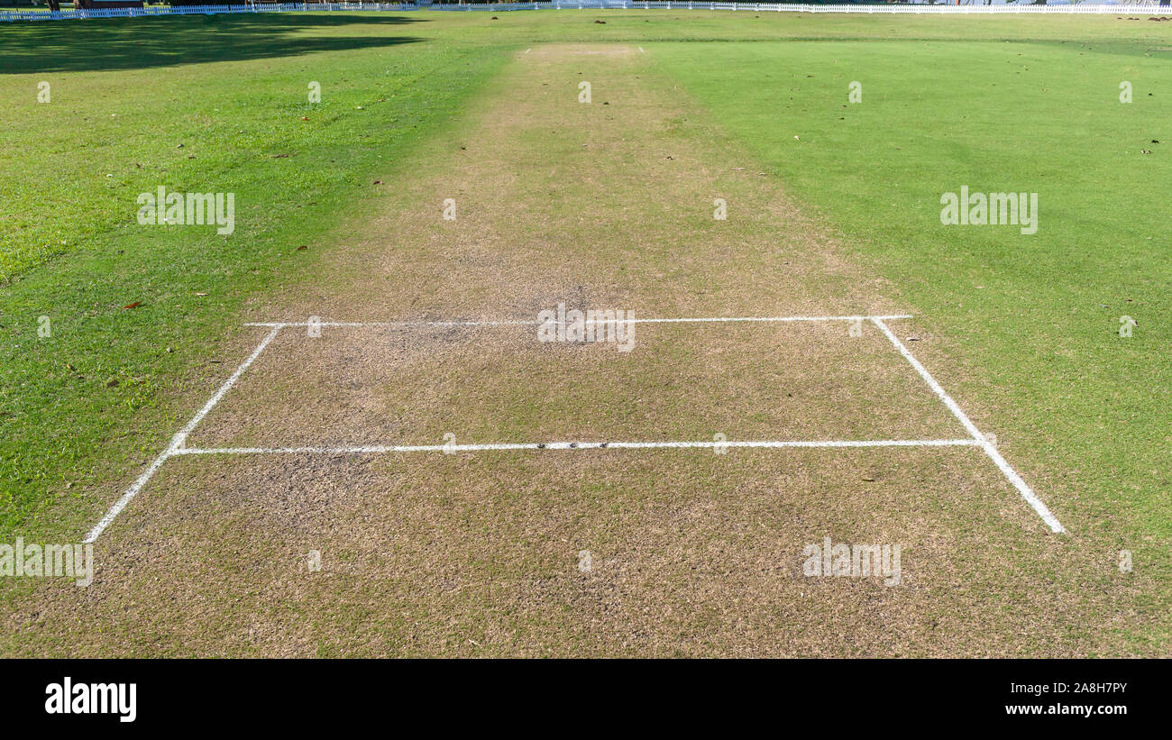 Scenic cricket grounds from white boundary fence of grass field astro ...