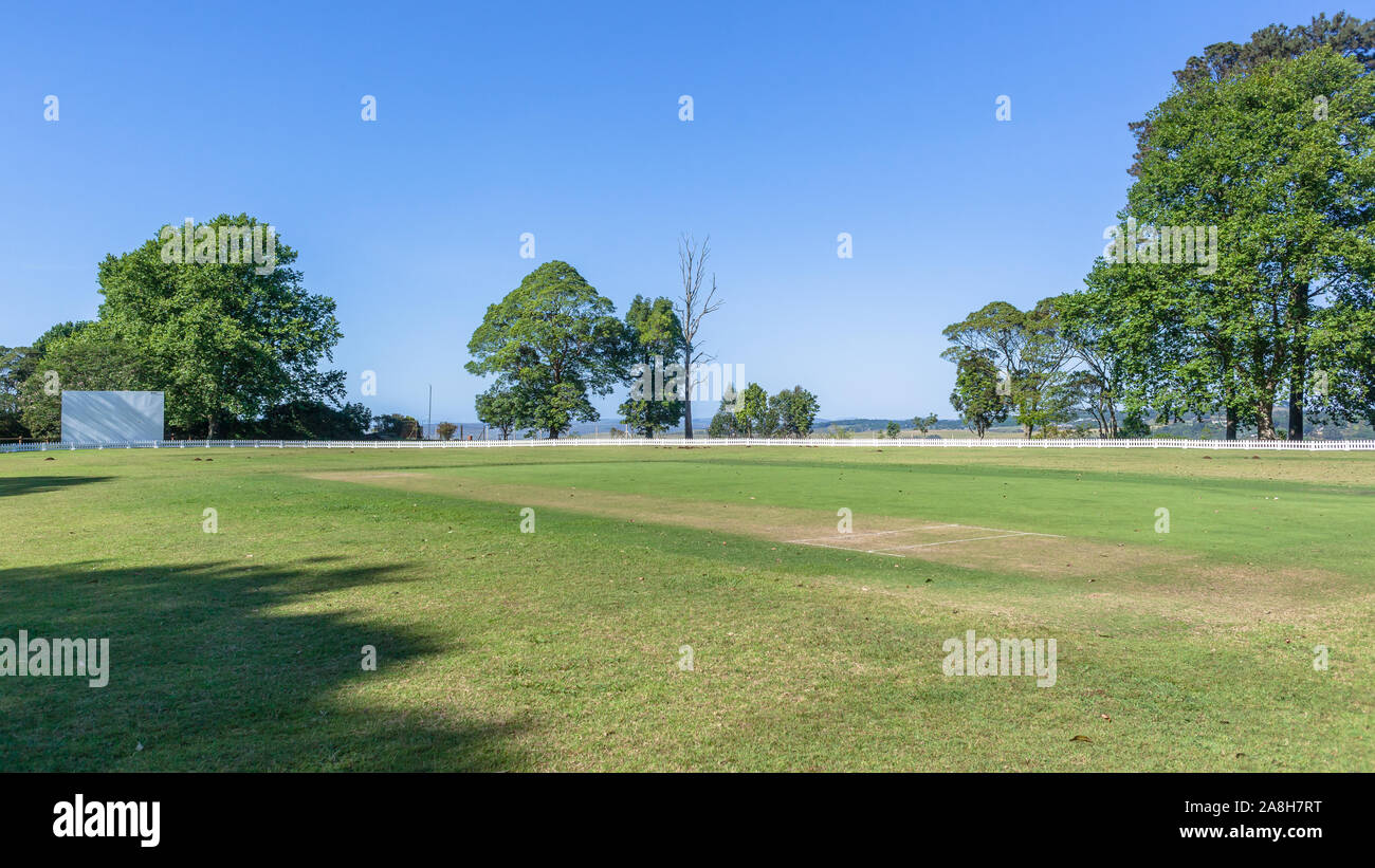 Scenic cricket grounds from white boundary fence of grass field astro ...