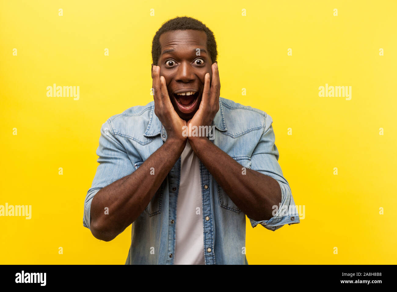 Oh my god, wow! Portrait of stunned shocked man in denim shirt holding ...