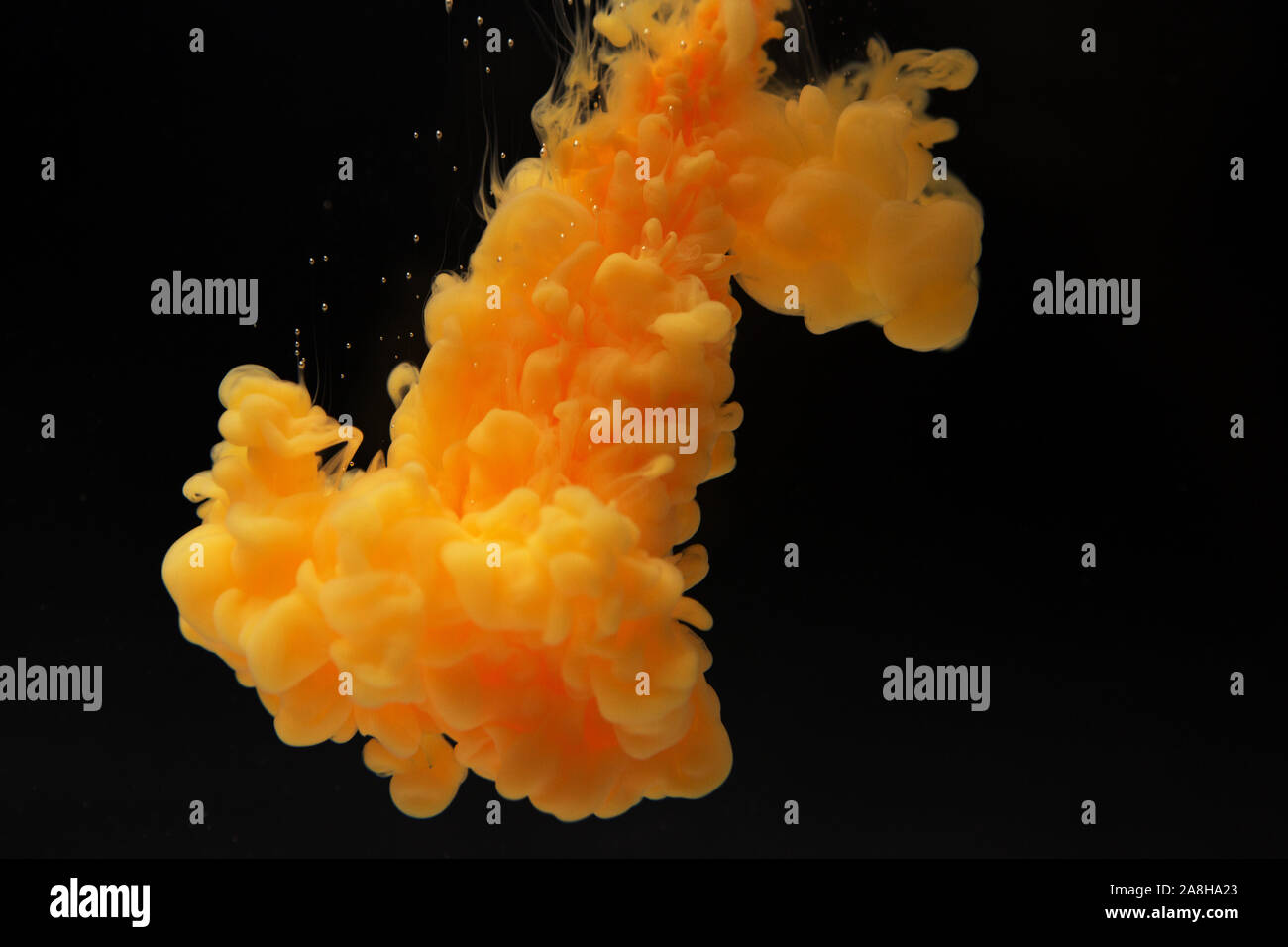 Abstract flowing liquid or orange color ink in water on a black ...