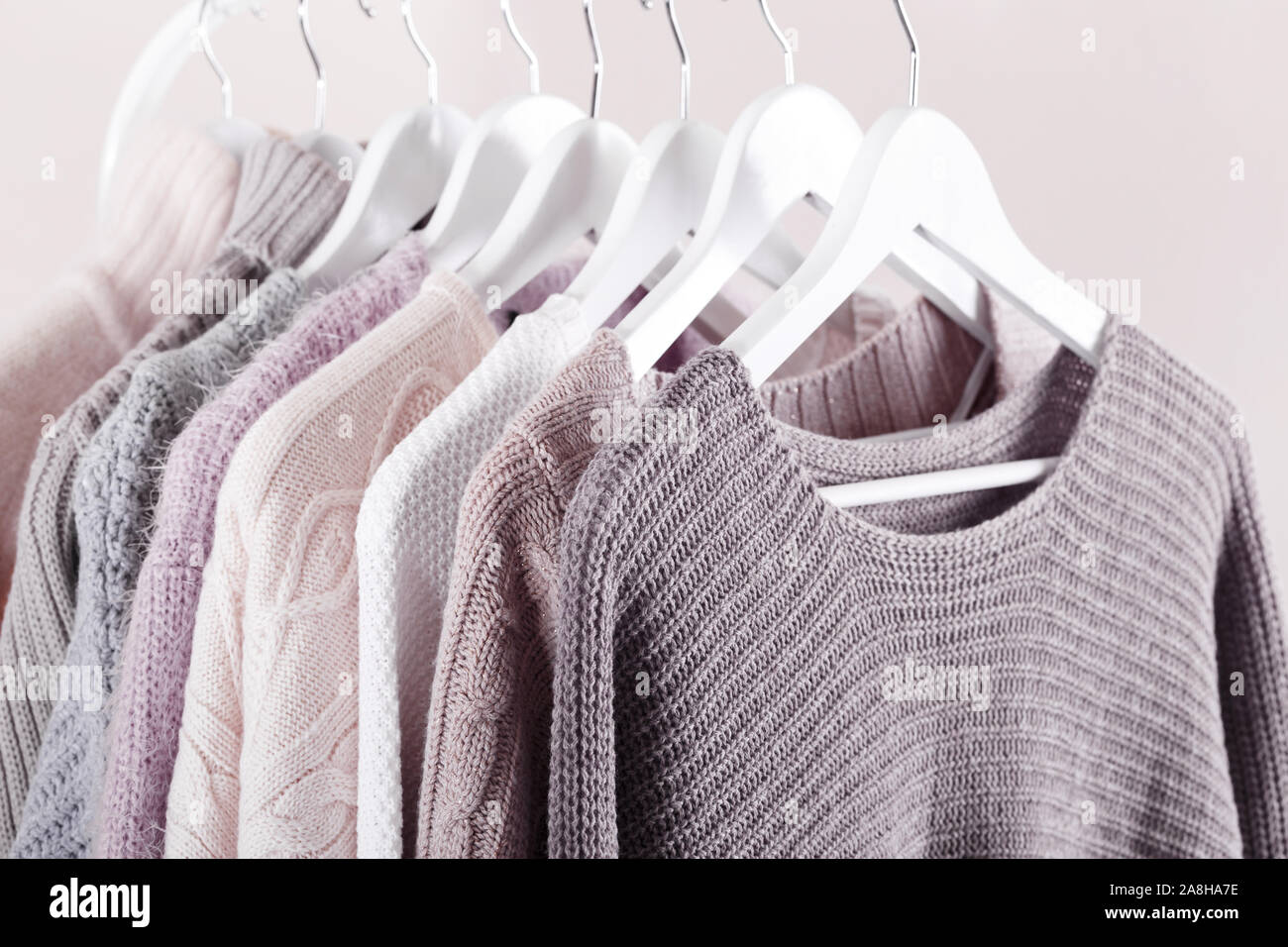 Warm knitted, autumn, winter clothes hanging on a rack, trending ...