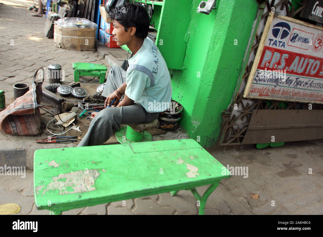 Indian man outside a shop selling car parts on Malik bazar in Kolkata ...