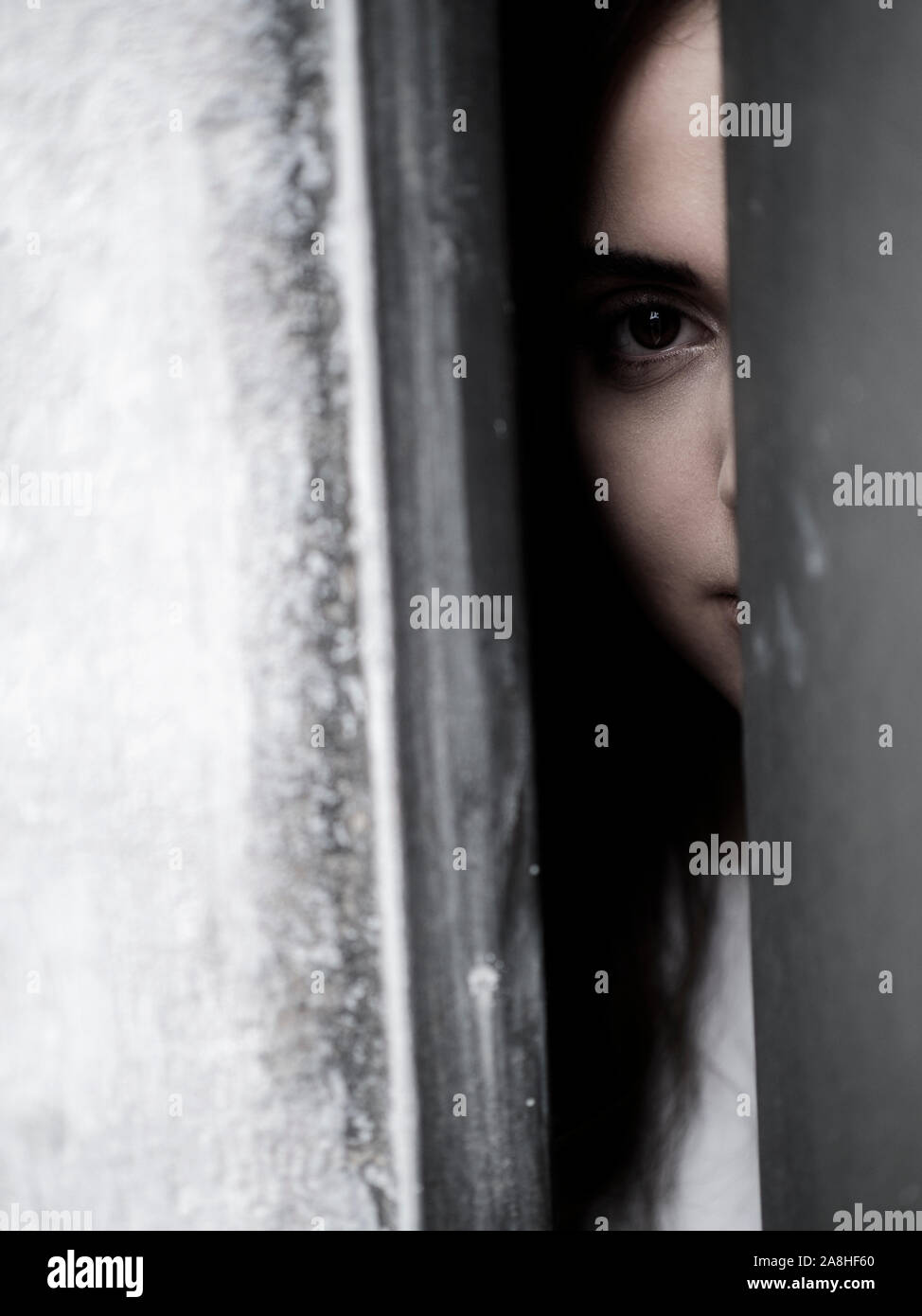 Beautiful young woman peeking Stock Photo - Alamy