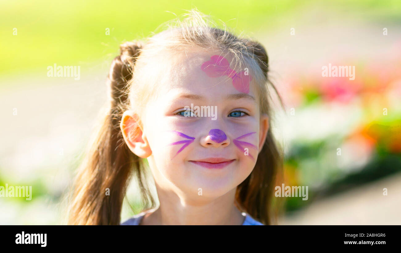 A preschool girl with paints on her face is smiling on the street Stock ...
