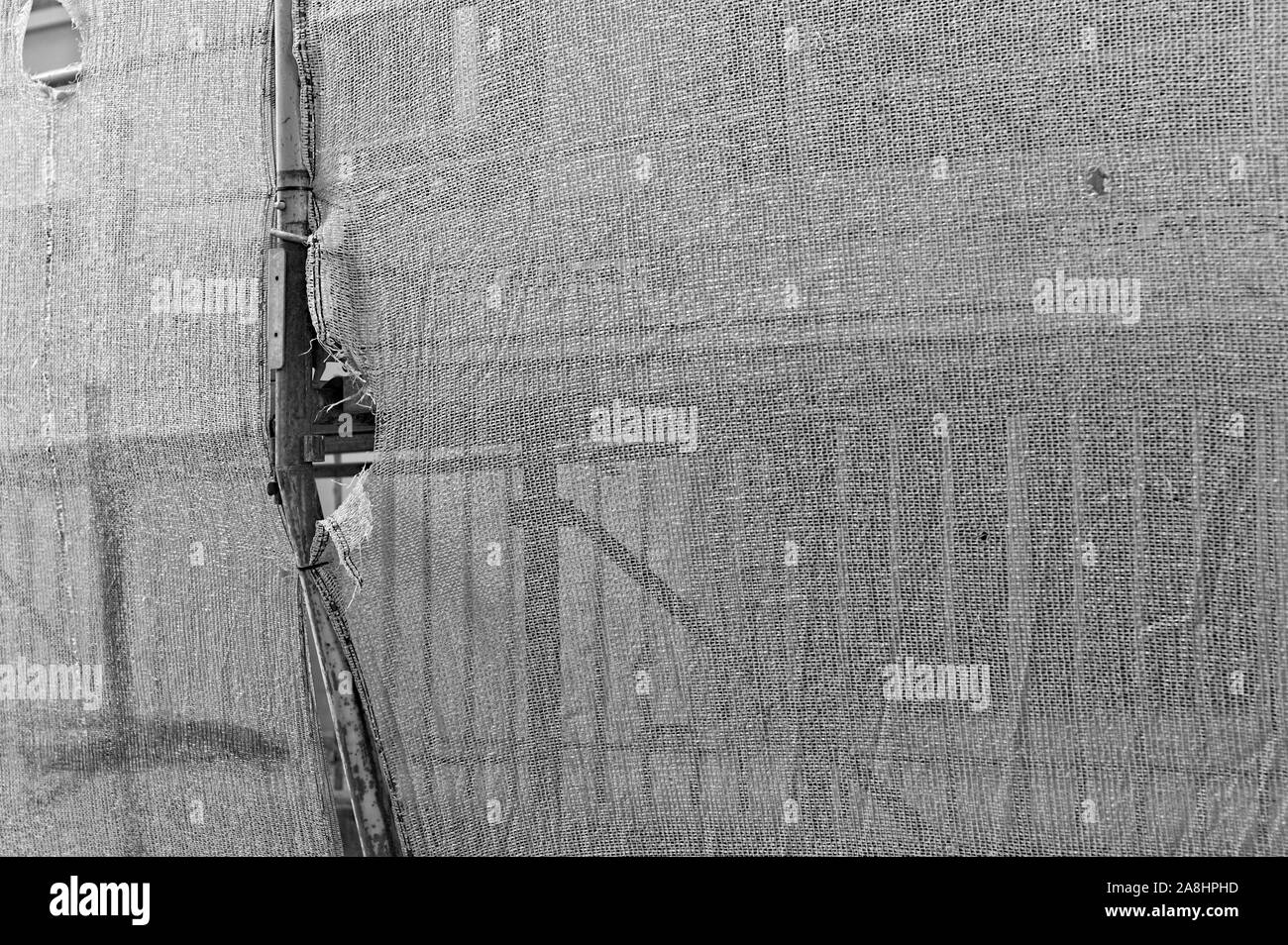 Detail of a rusty scaffolding through a white plastic fiber net ...