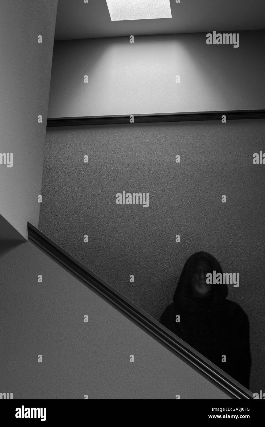 Hooded monk, apparition standing in window light at foot of stairs ...