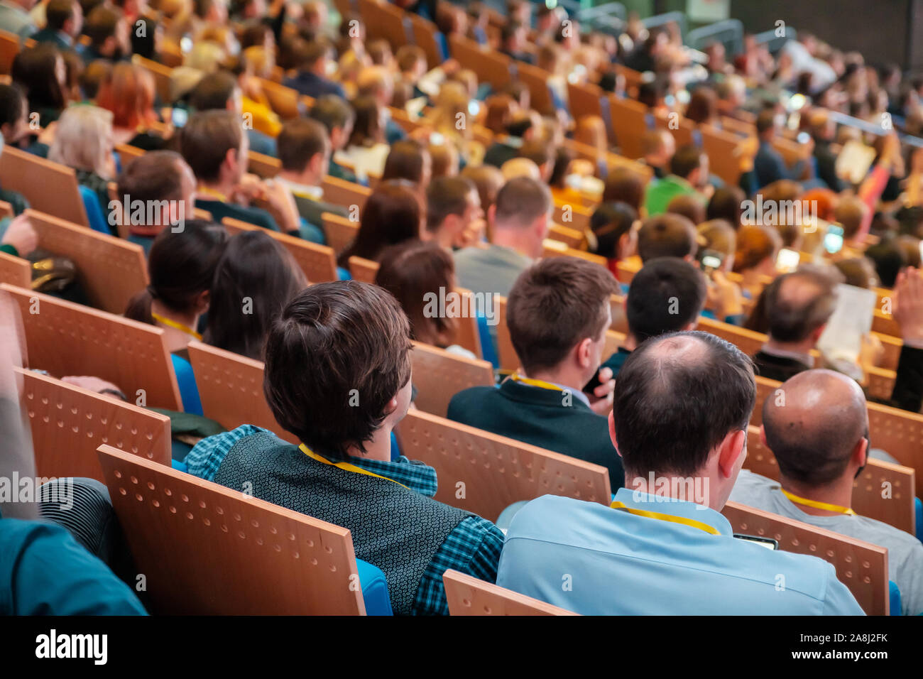 Business conference attendees sit and listen to lecturer, rear top view ...