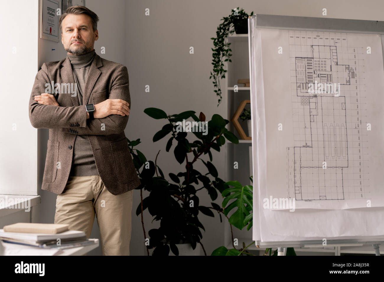Serious architect or engineer with his arms crossed on chest standing ...