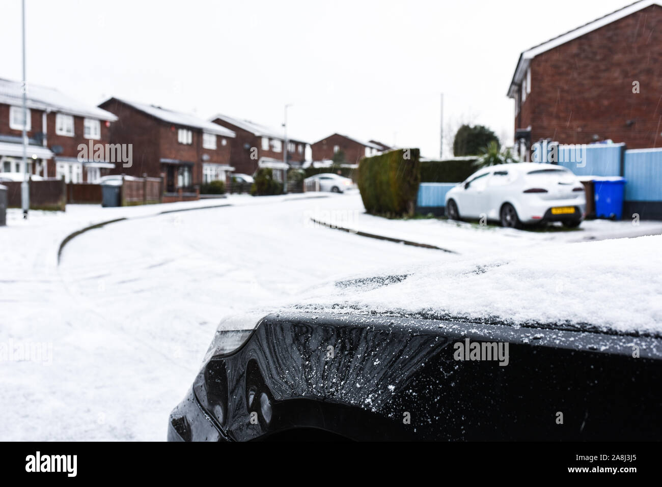 Snow covered cars, recycling bins, roads and houses at night in Longton ...