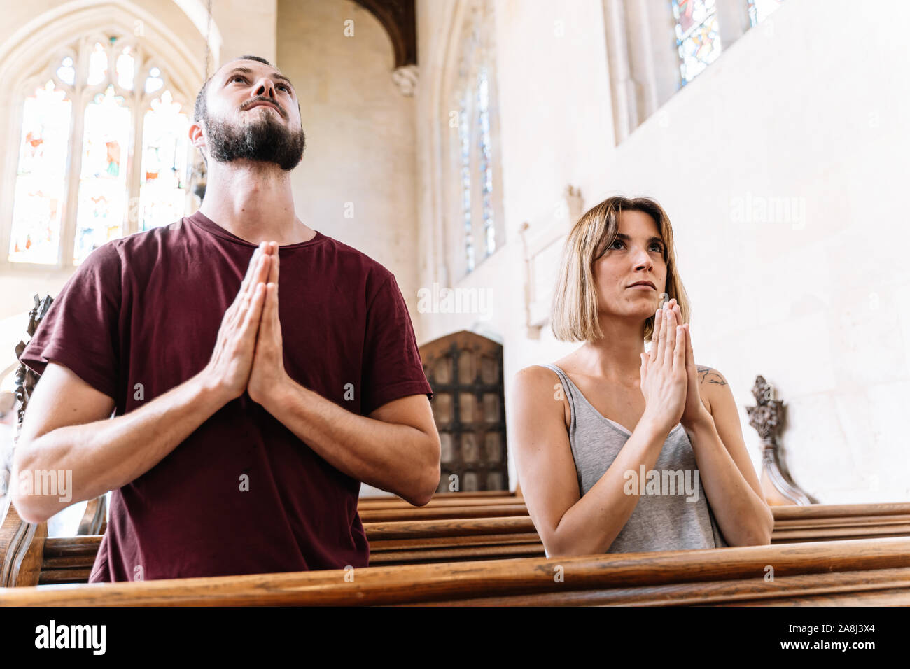 Young couple praying in a church looking up at the sky. Travel concept ...