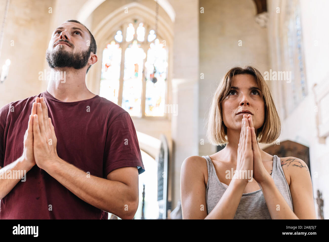 Stock photo of a young couple praying in a church with the window in ...