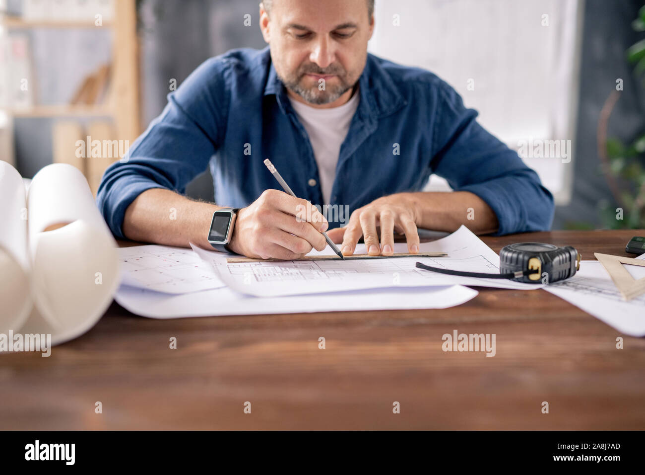 Bearded mature engineer using pencil and ruler while drawing line on ...