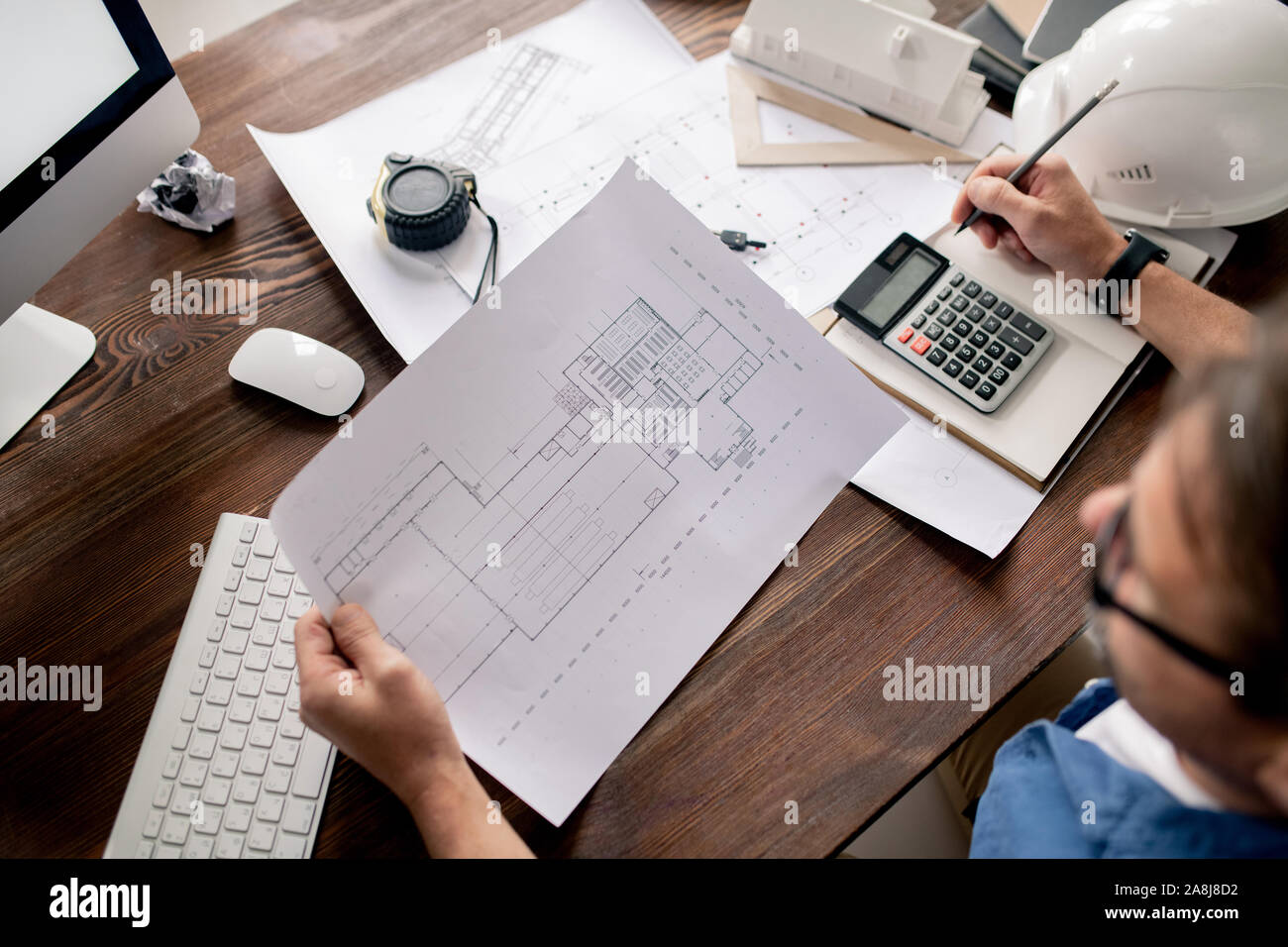 Paper with sketch held by engineer looking at blueprint and making ...