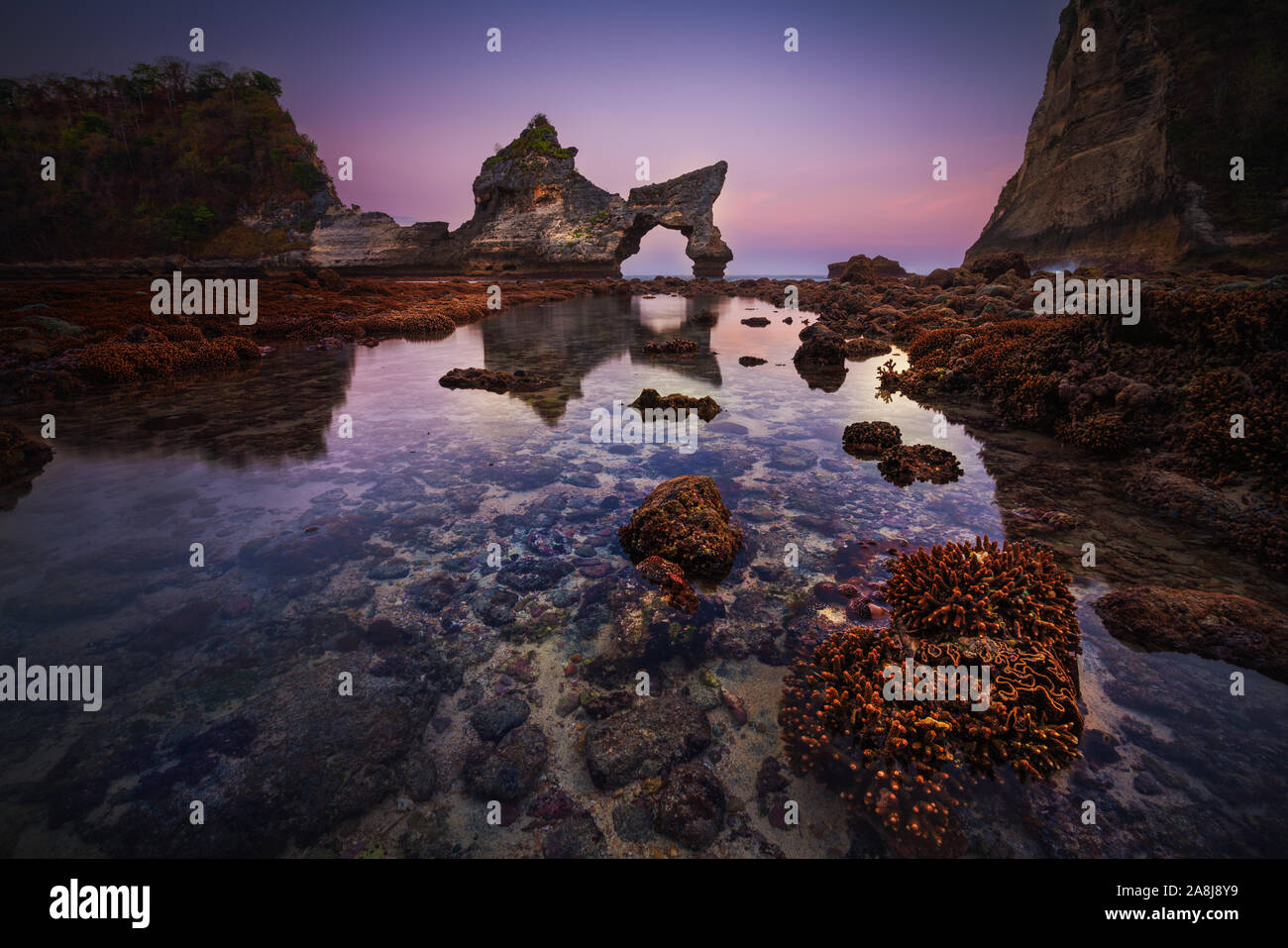 Atuh beach after sunset. Coral reef in low tide. Beautiful arch and ...