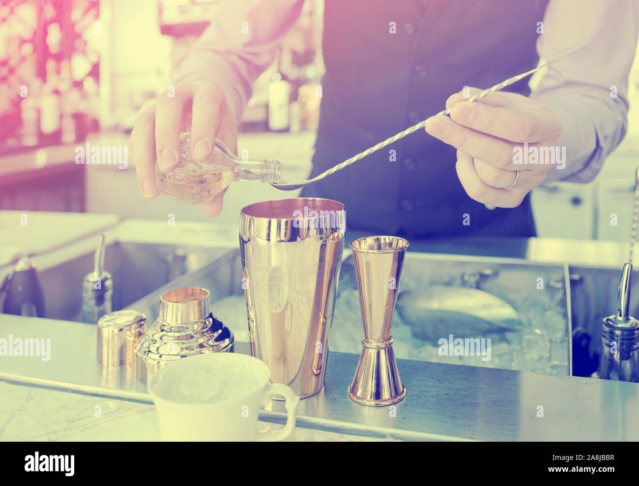 Bartender is adding ingredient in shaker at bar counter, toned image Stock Photo - Alamy