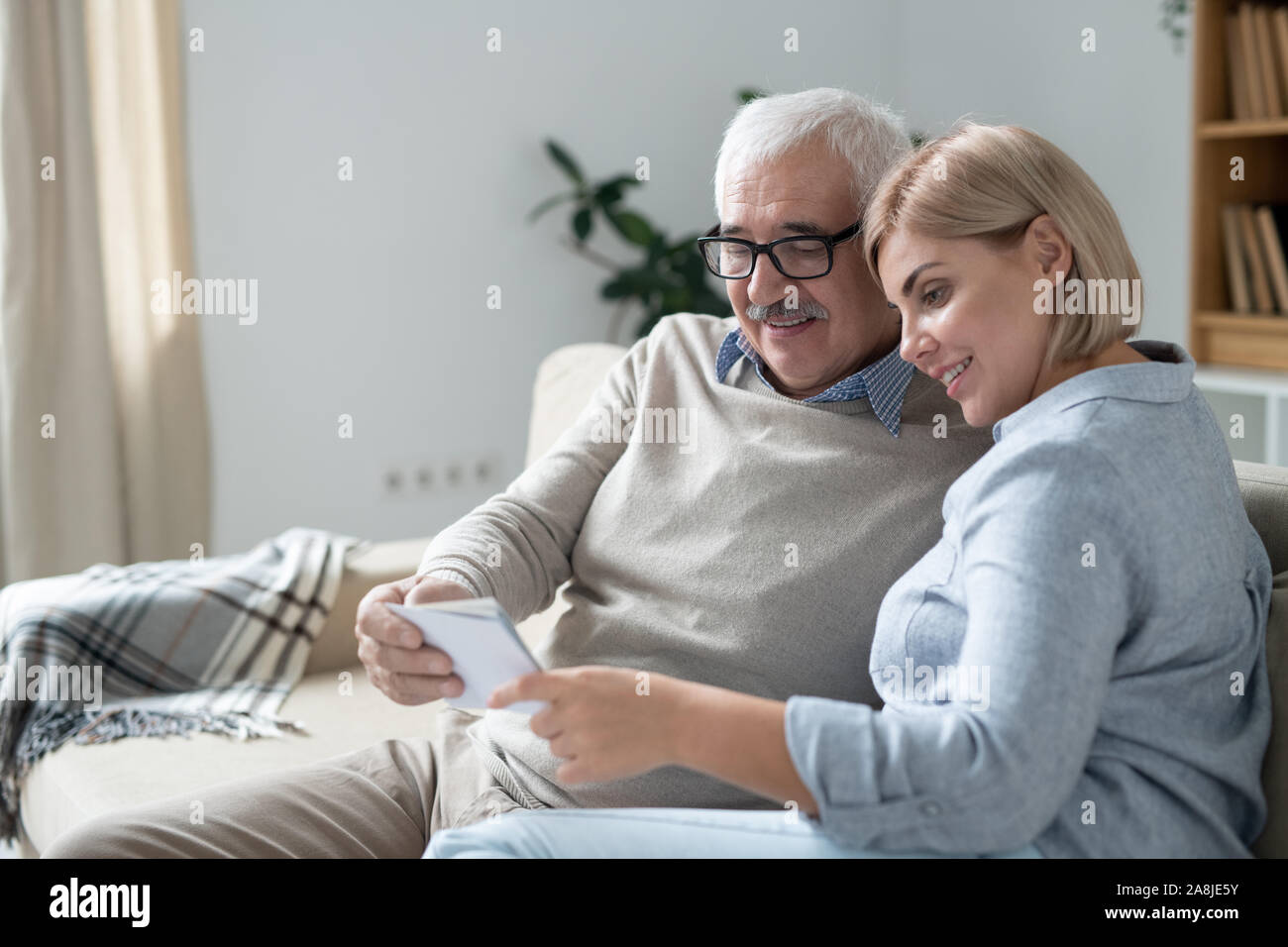 Senior man and his young daughter looking at one of their family ...