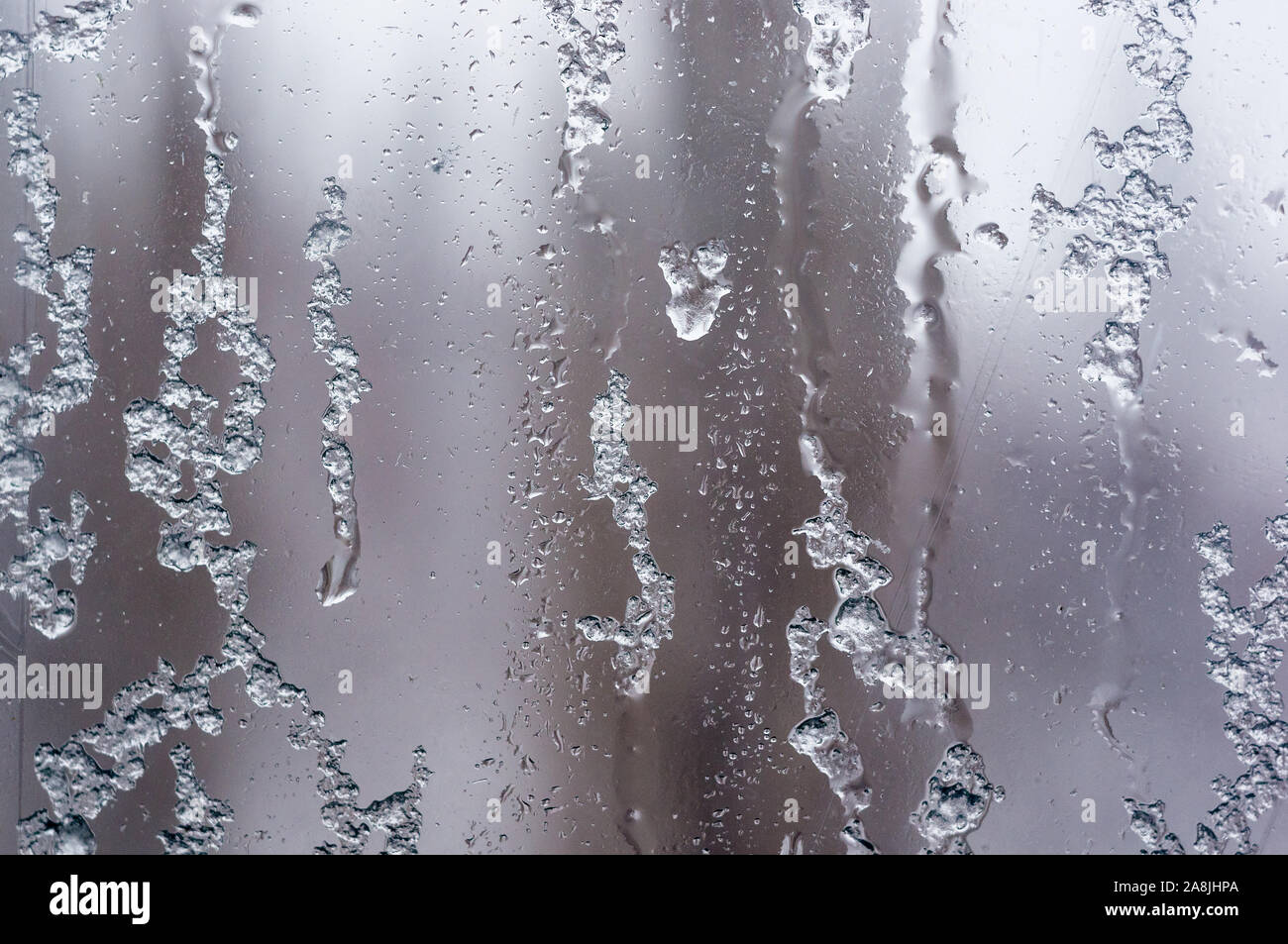 glass in the window covered with wet melting snow, close-up, macro ...