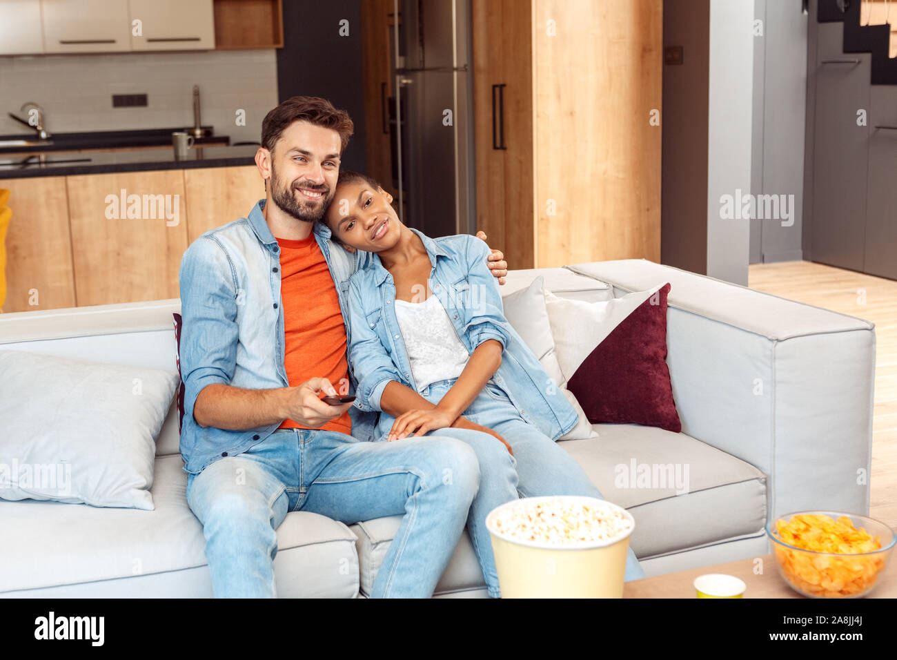 Mixed Race Marriage. Young man and woman hugging watching tv program ...