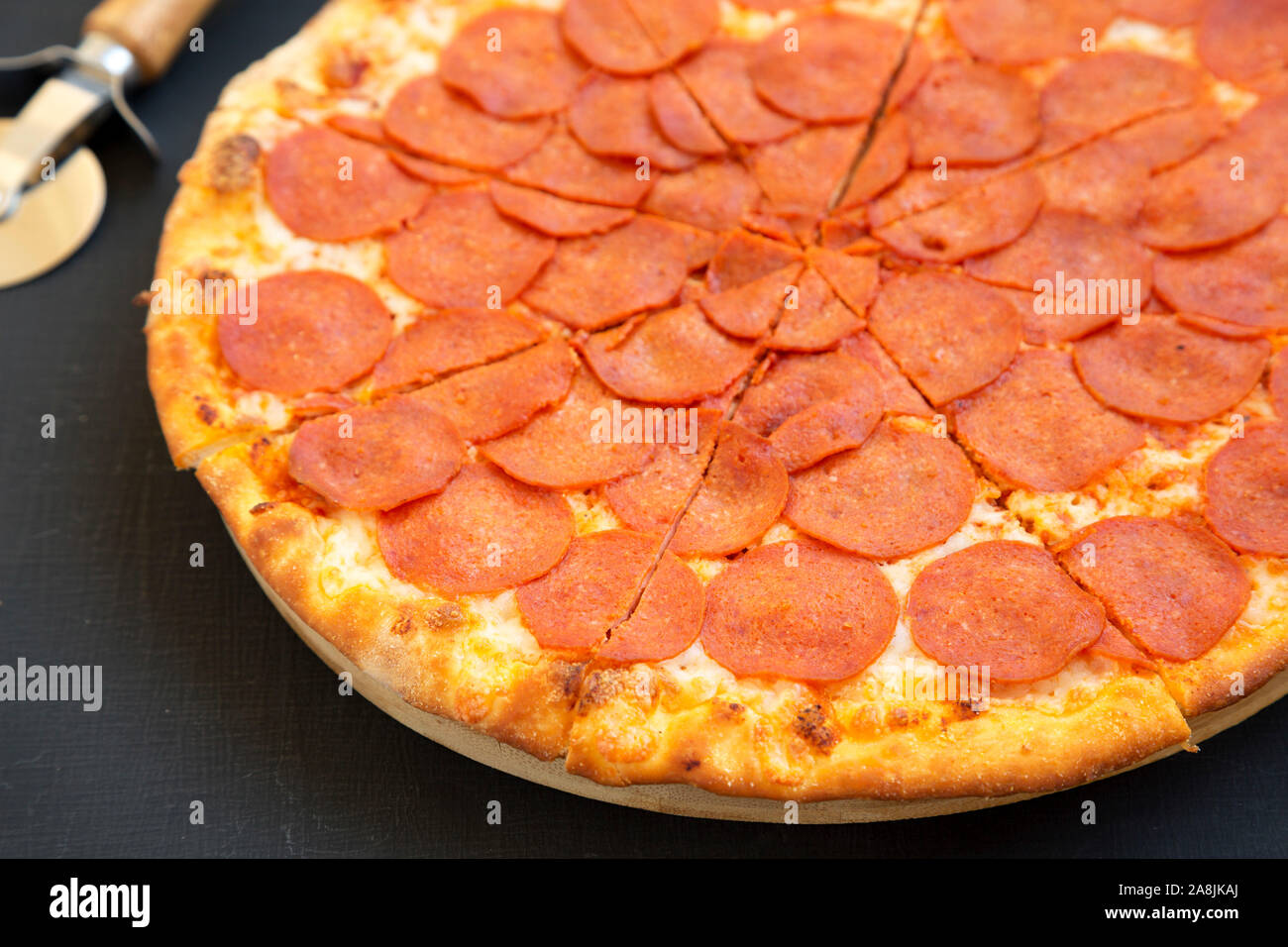Tasty Pepperoni pizza over black background, side view. Close-up Stock ...