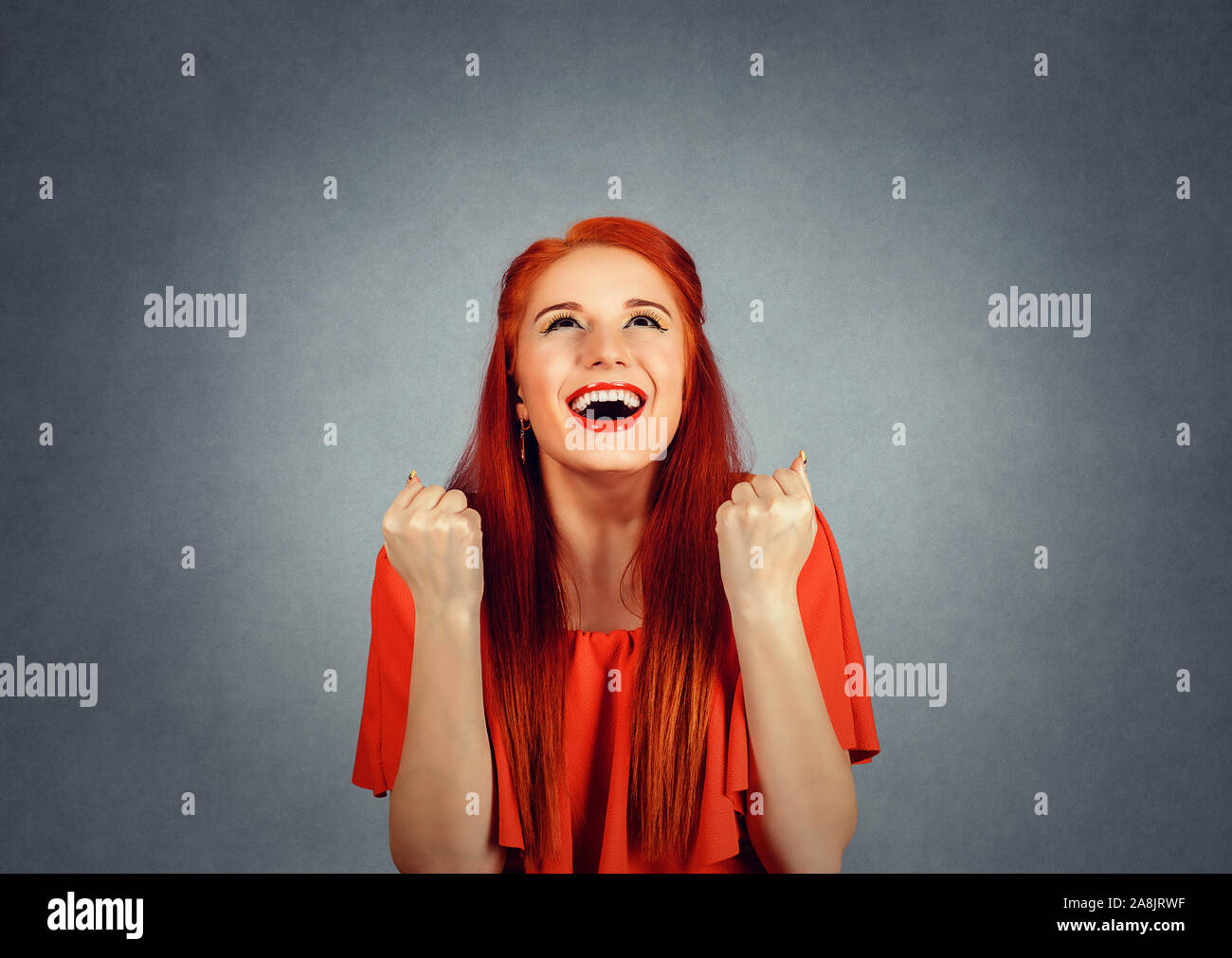 portrait happy redhead woman in red dress exults pumping fists ecstatic ...