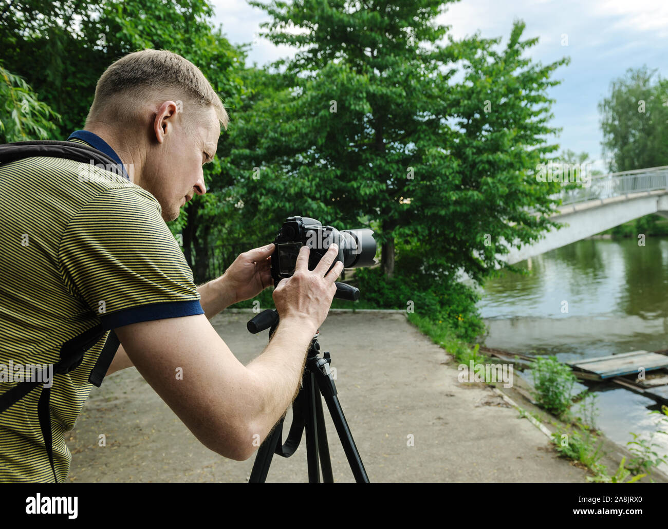 The photographer is photographing with a tripod. He is adjusting the ...