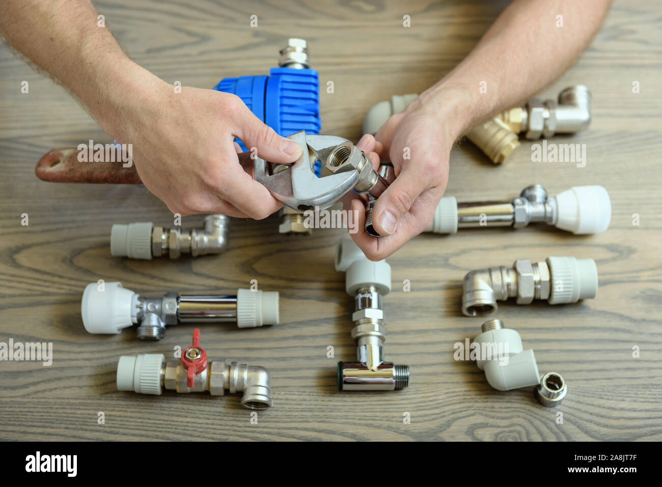 A worker is connecting elements of the plumbing with the adjustable ...