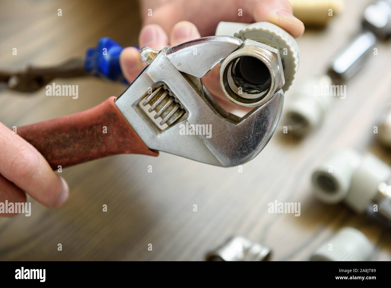 A worker is connecting elements of the plumbing with the adjustable ...