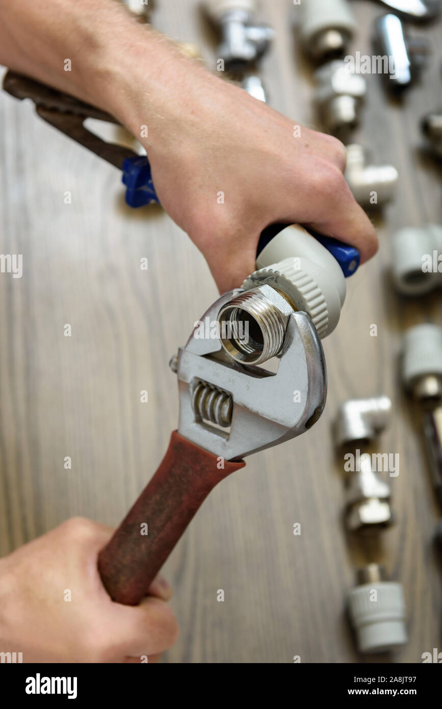 A worker is connecting elements of the plumbing with the adjustable ...