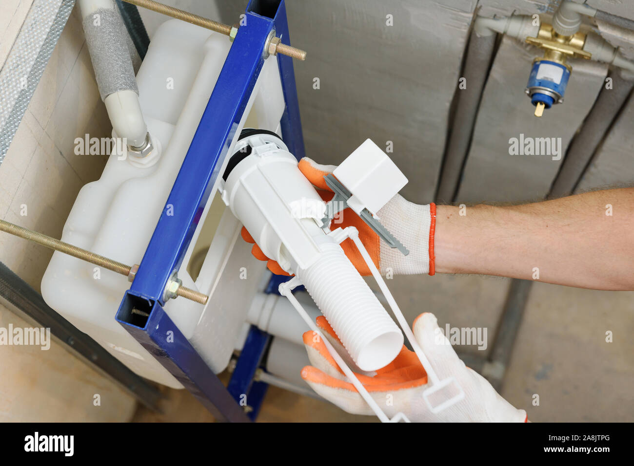 A worker is inserting the toilet flushing valve into the built-in tank ...
