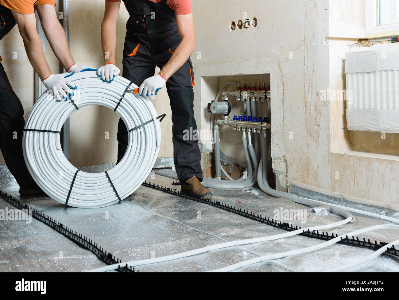 Workers are installing a pipe for the warm floor in the apartment. They ...