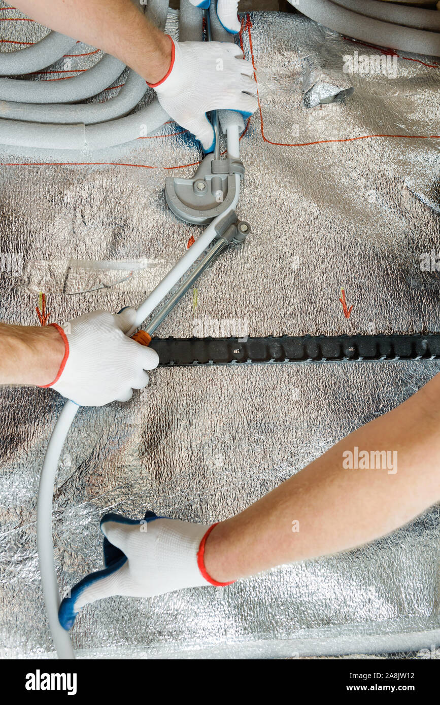 Workers are installing a pipe for the warm floor in the apartment. They ...