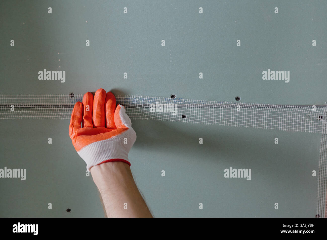 A worker is attaching the mesh to the seams between the plasterboards ...