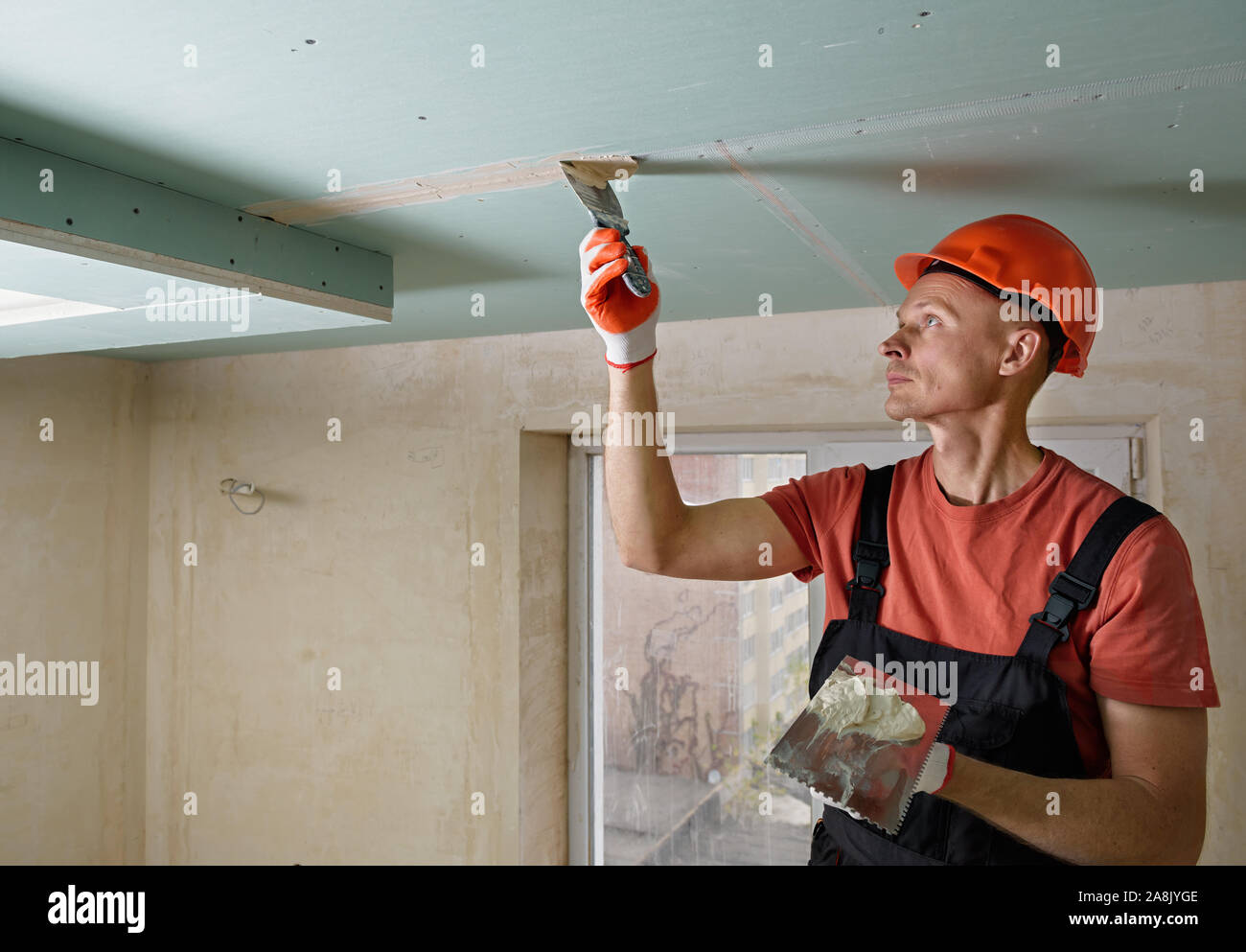 The worker is filling the plasterboards seams the gypsum putty Stock ...