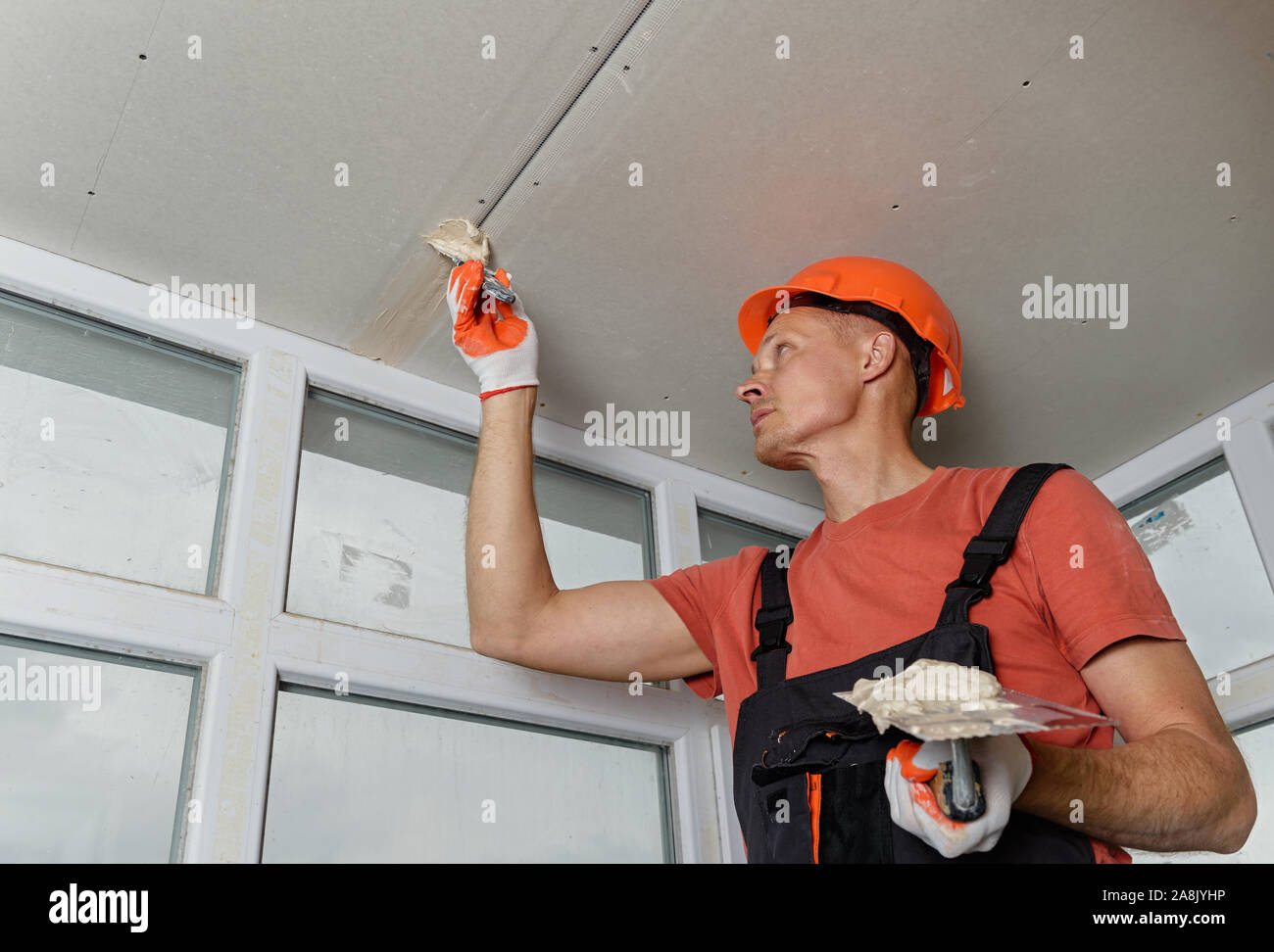The worker is filling the plasterboards seams the gypsum putty Stock ...