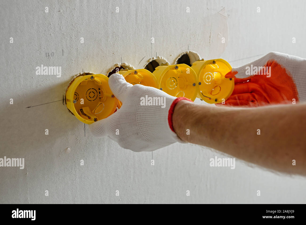 A worker is installing a group of socket boxes into drywall Stock Photo ...