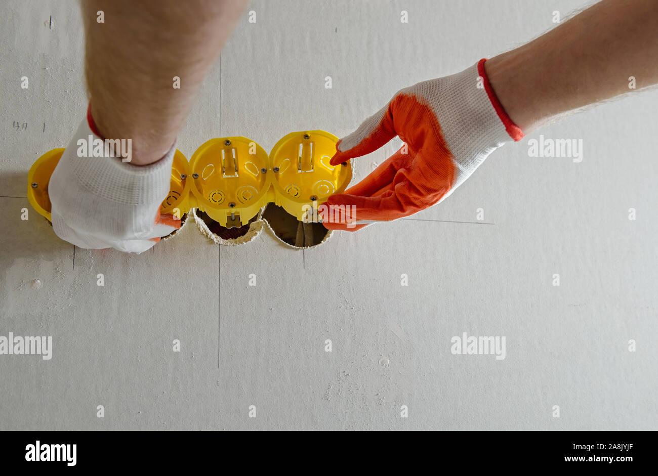 A worker is installing a group of socket boxes into drywall Stock Photo ...